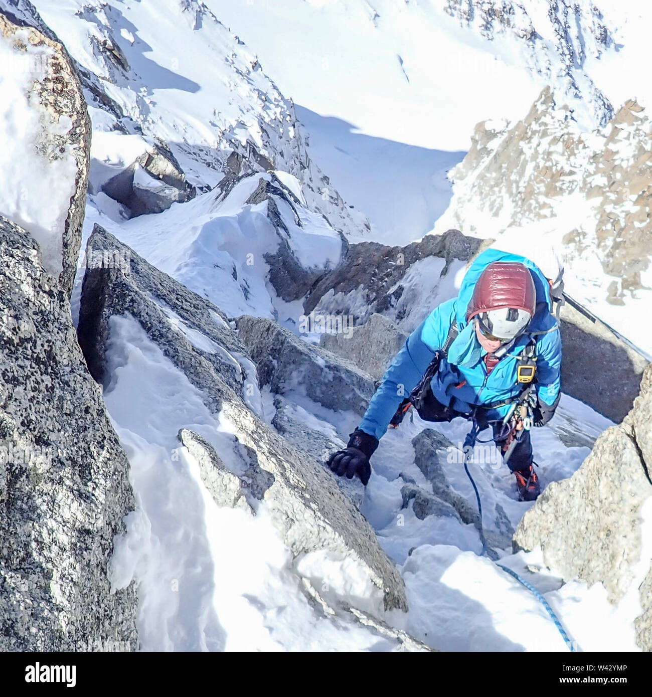 A woman mountaineer climbs a steep mixed gully on the Cosmiques Arete ...