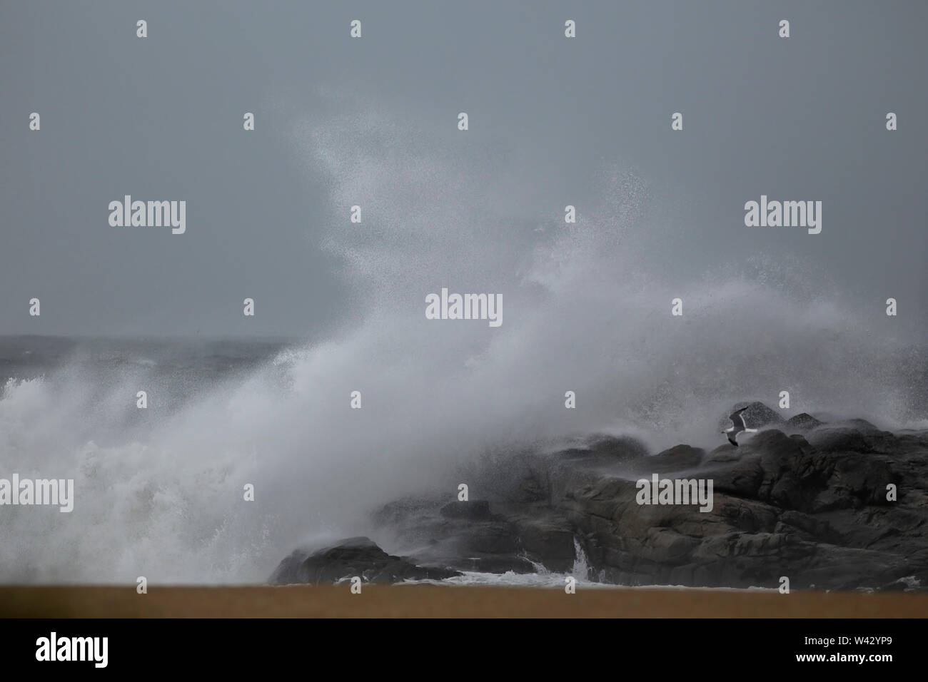 Big wave over beach rocks Stock Photo - Alamy
