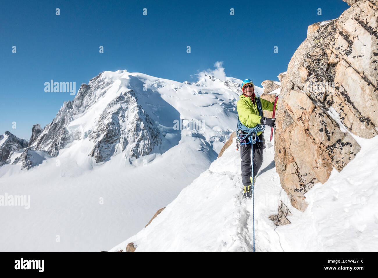 Smiling alpinist navigates steep snow traverse on the Cosmiques Ridge ...