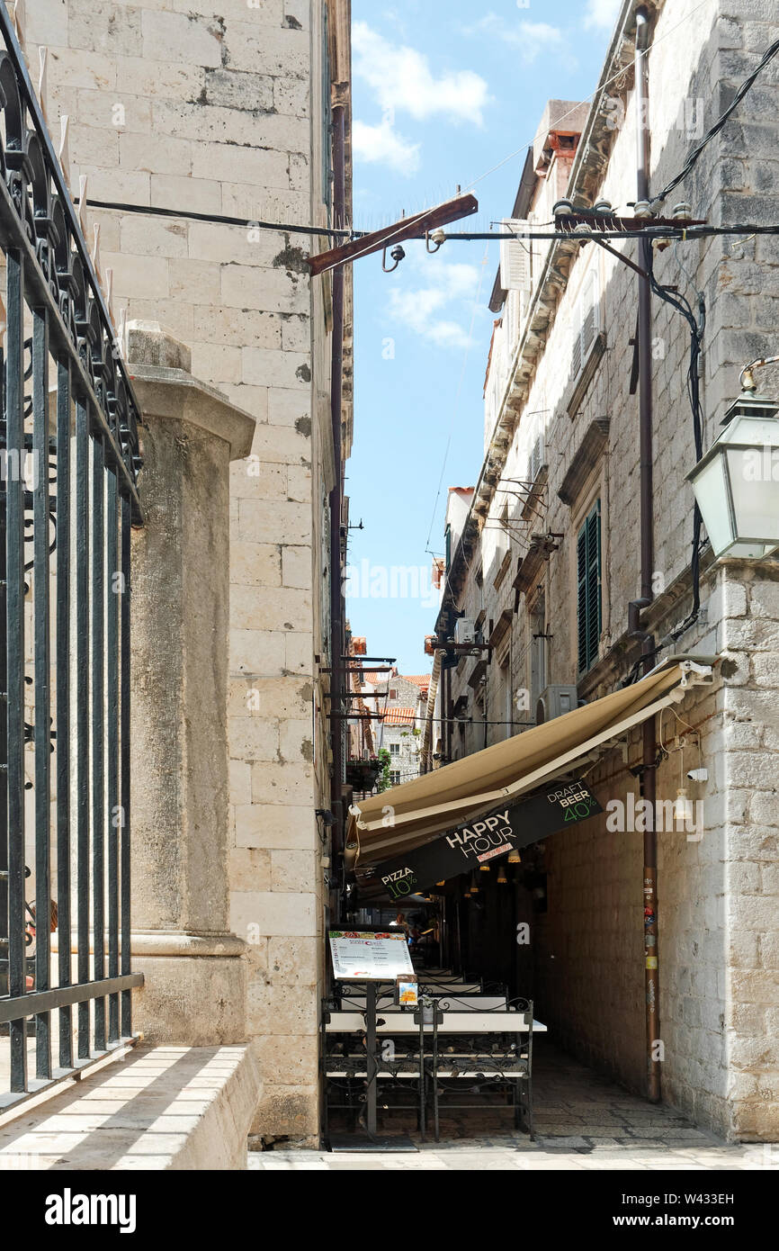 narrow pedestrian street; restaurant, outdoor tables, awning, stone ...