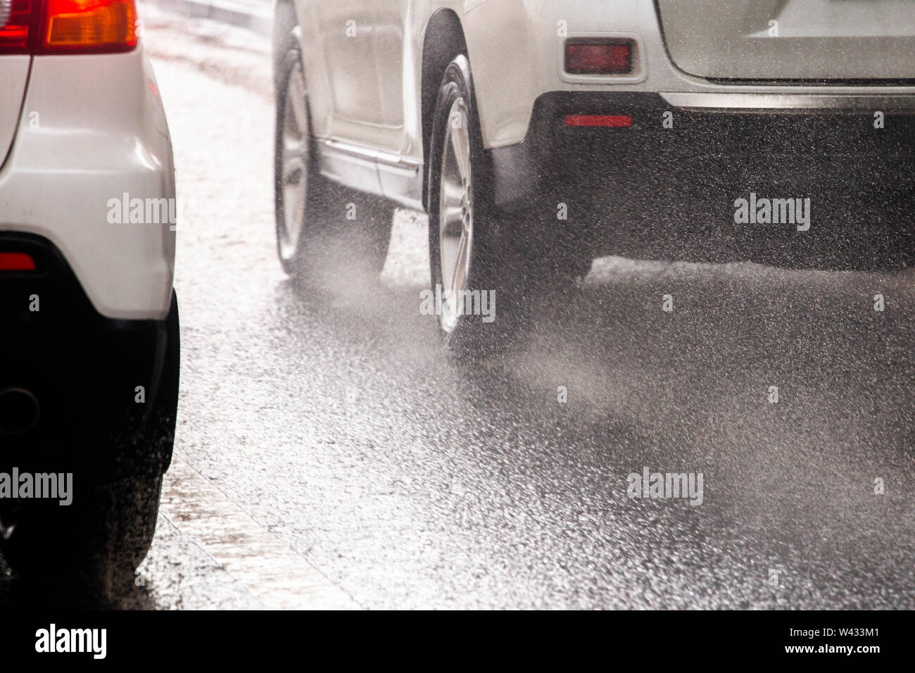 rain water splash flow from wheels of white cars moving fast in ...