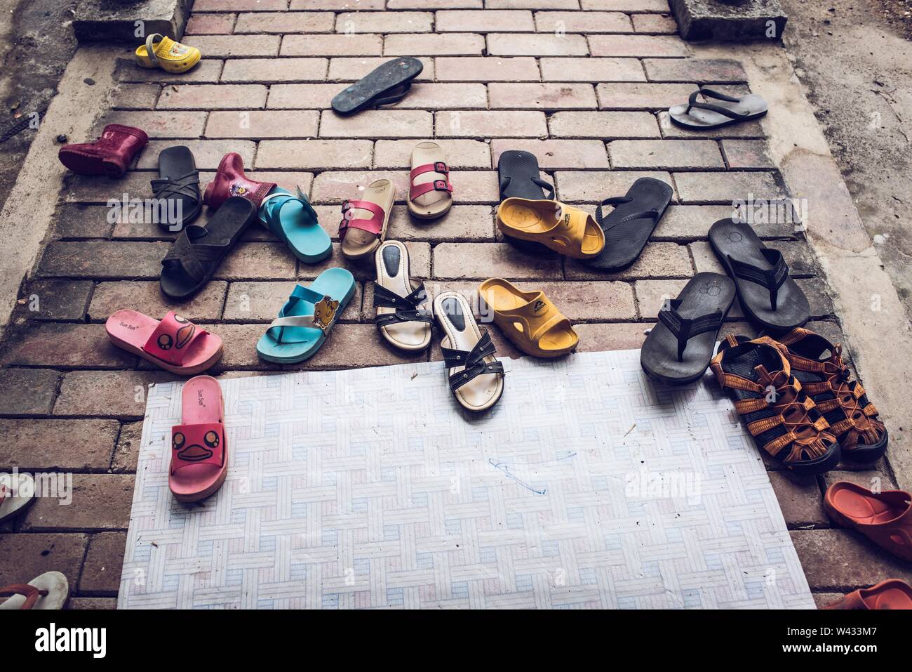 High angle shot of many differently colored types of sandals on a porch ...