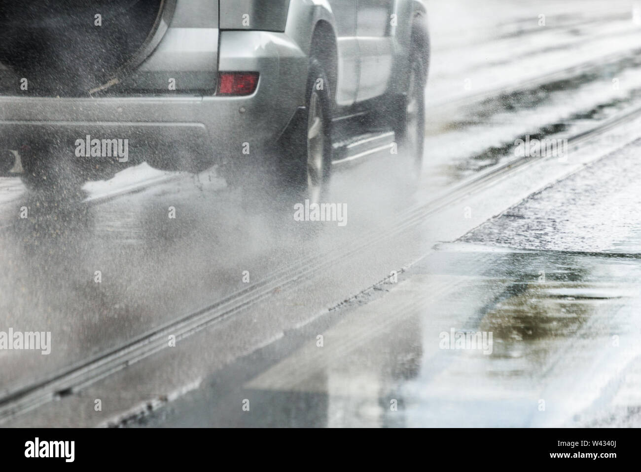 rain water splash flow from wheels of silver crossover car moving fast ...