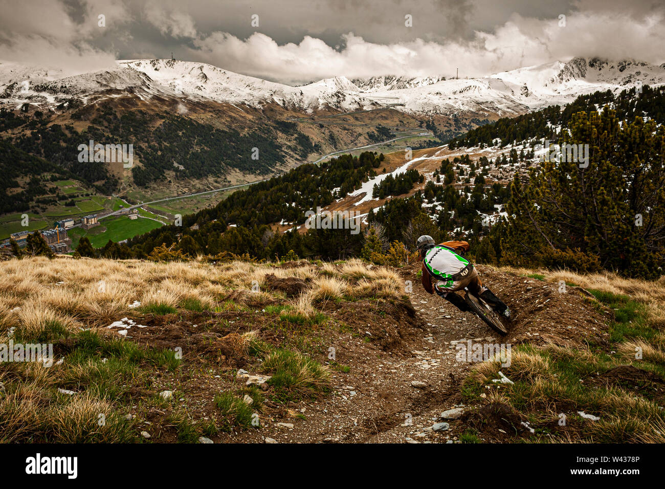 A mountain biker riding the bike park trails in early summer. Snowy ...