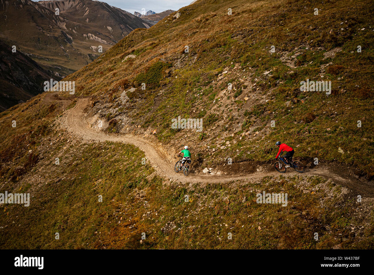 Mountain bikers riding a purpose built trail in the bike-park with deep ...