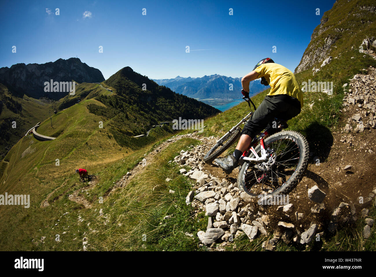 Two mountain bikers riding down a very steep and narrow rocky trail ...