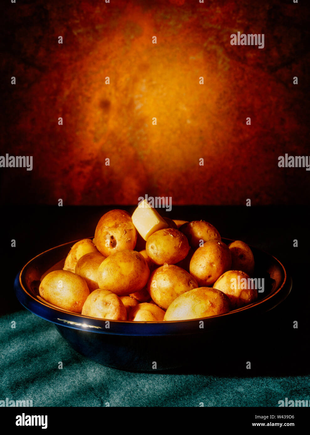 Blue bowl full of new potatoes with a knob of butter on top, shot with ...