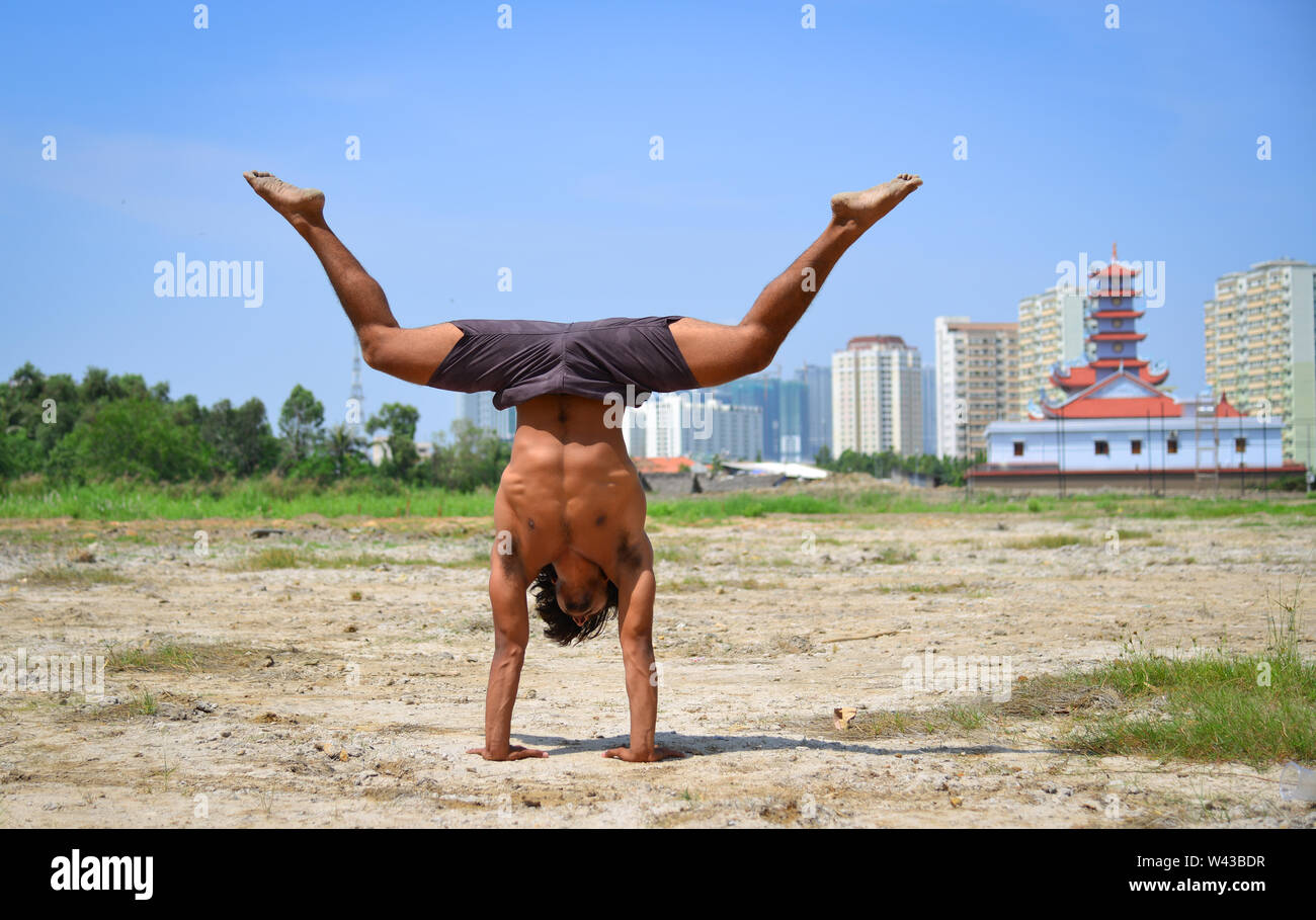Athletic muscular young Indian man doing yoga exercise in the park ...
