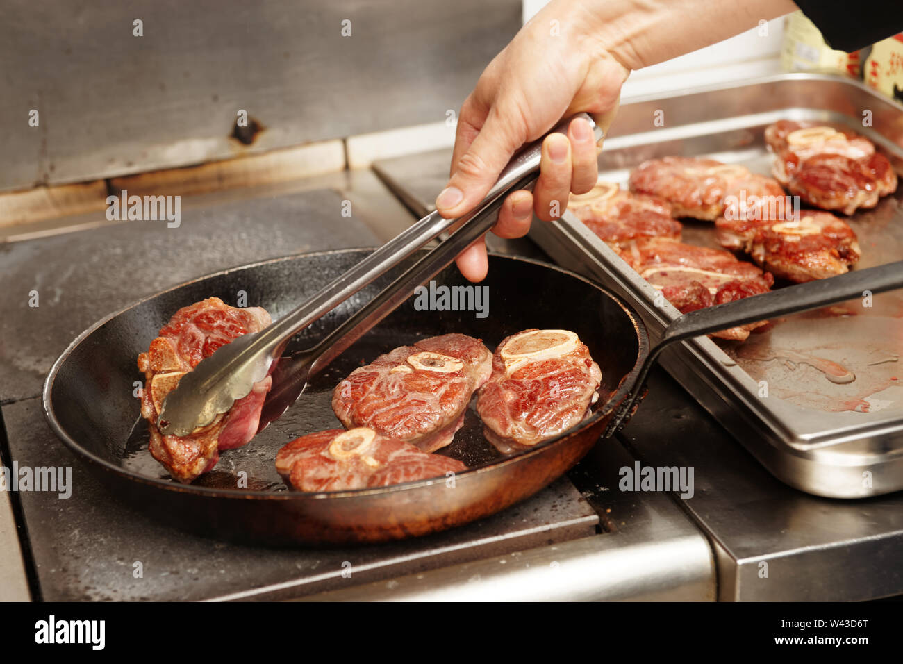 Chef is frying meat at commercial kitchen Stock Photo - Alamy