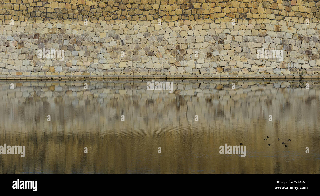 Ancient stone wall of Japanese castle with the protect canal in Osaka ...
