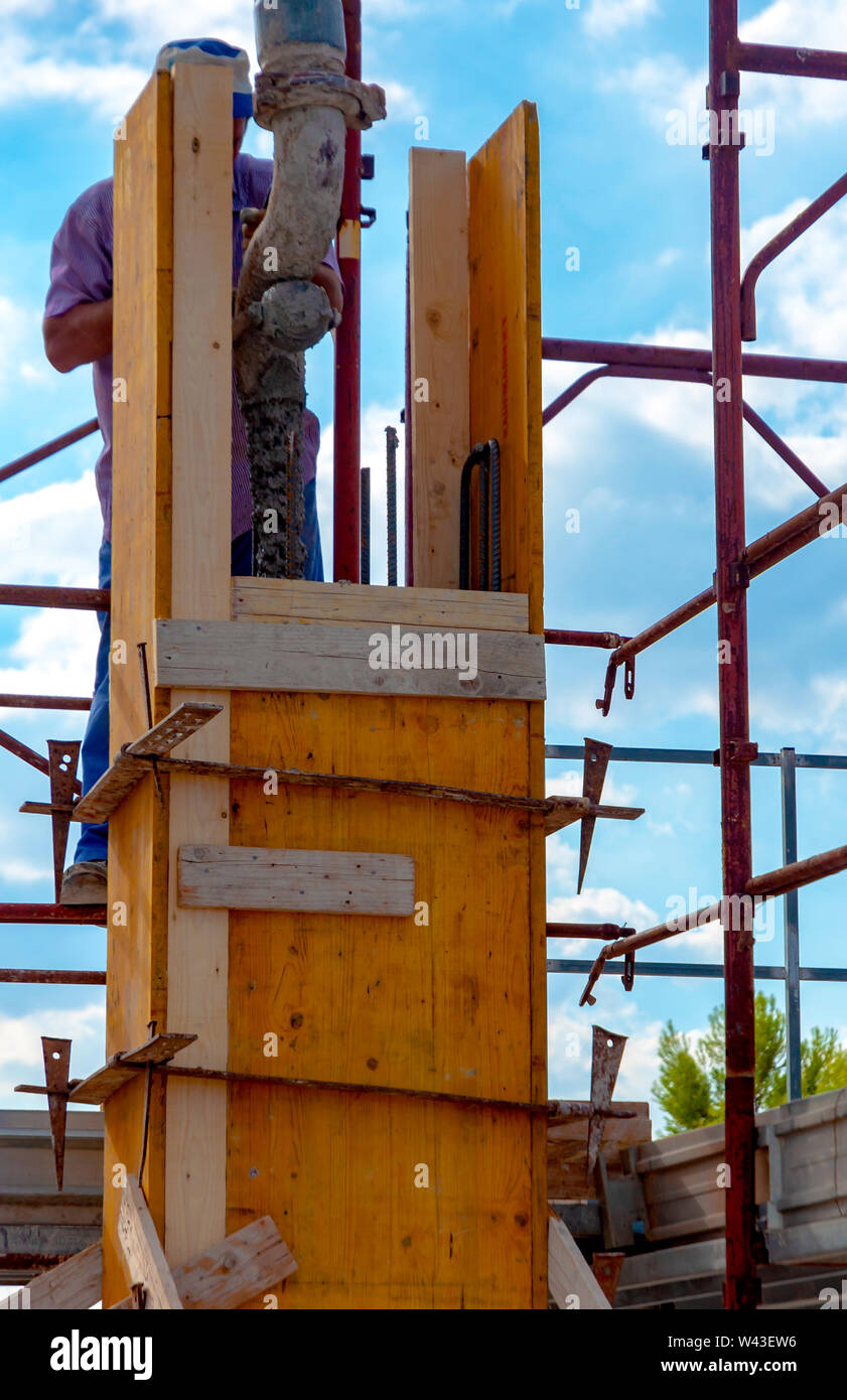 Construction worker pouring concrete into wooden formwork of a concrete ...
