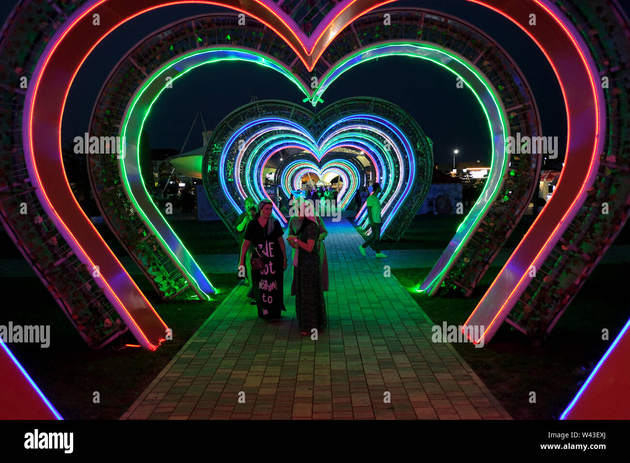 Chechen women walk at night through an illuminated heart-shaped tunnel ...