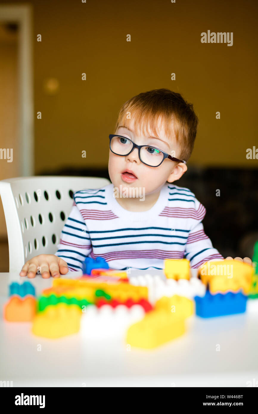 little ginger boy with glasses with syndrome dawn playing with color ...