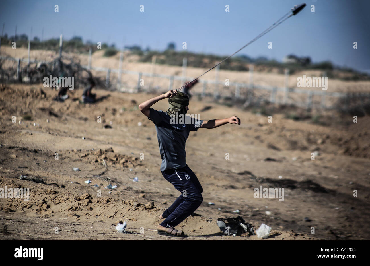 A Palestinian demonstrator uses a slingshot to throw stones at Israeli ...