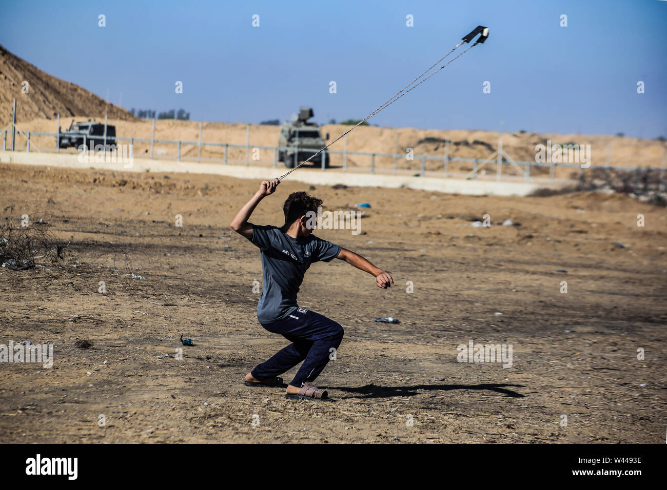 A Palestinian demonstrator uses a slingshot to throw stones at Israeli ...