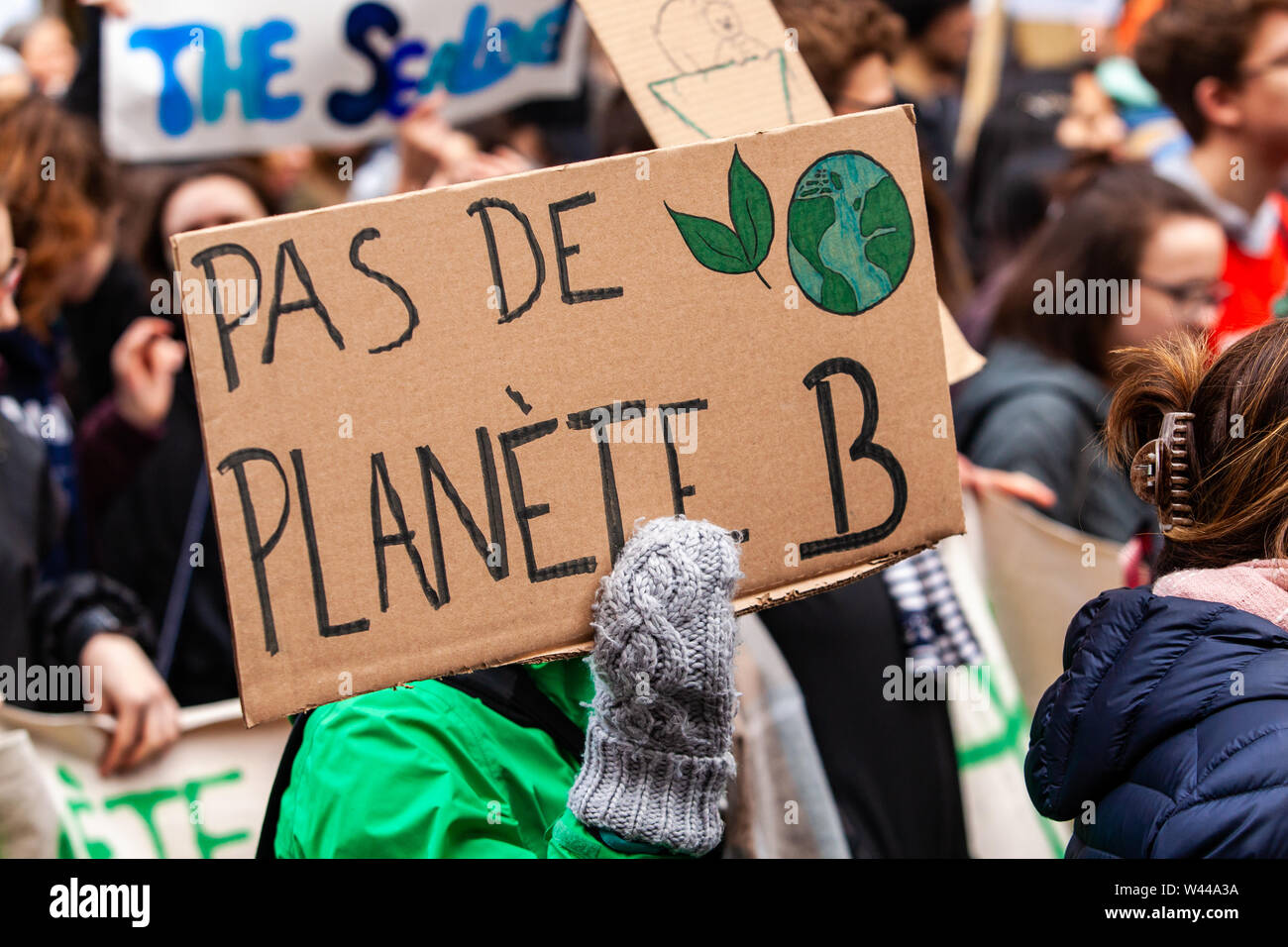 A cardboard sign is seen closeup with French words saying no planet b ...