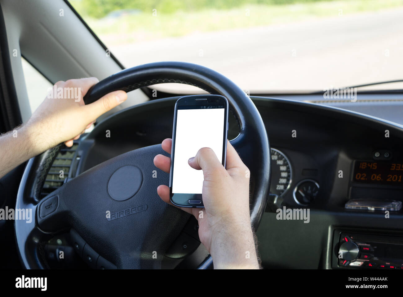 Car driver presses the blank screen of smartphone with his thumb while ...