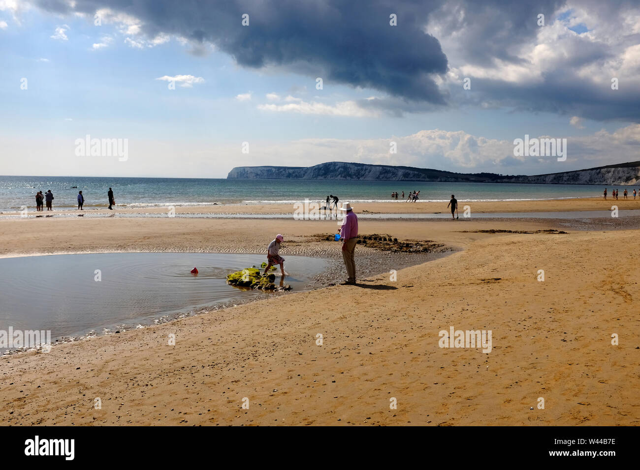 A summer beach scene at low tide with several beach goers in the ...