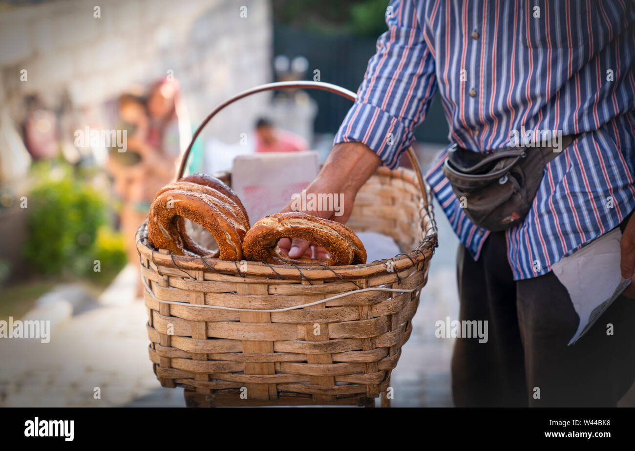 Street vendor selling simit (bread with sesame seeds) in basket and ...