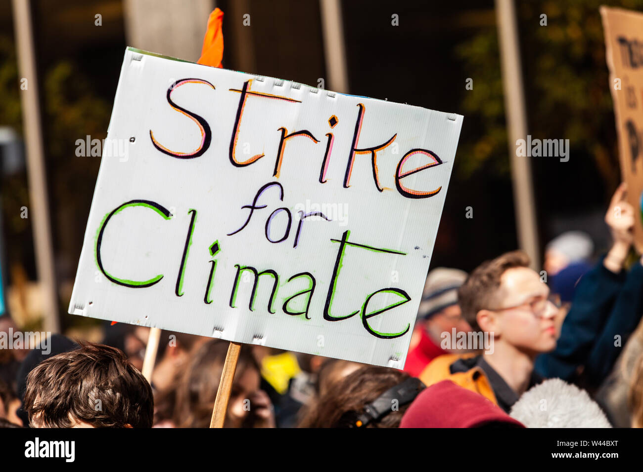 A cardboard placard is seen close-up on a crowded street of ...