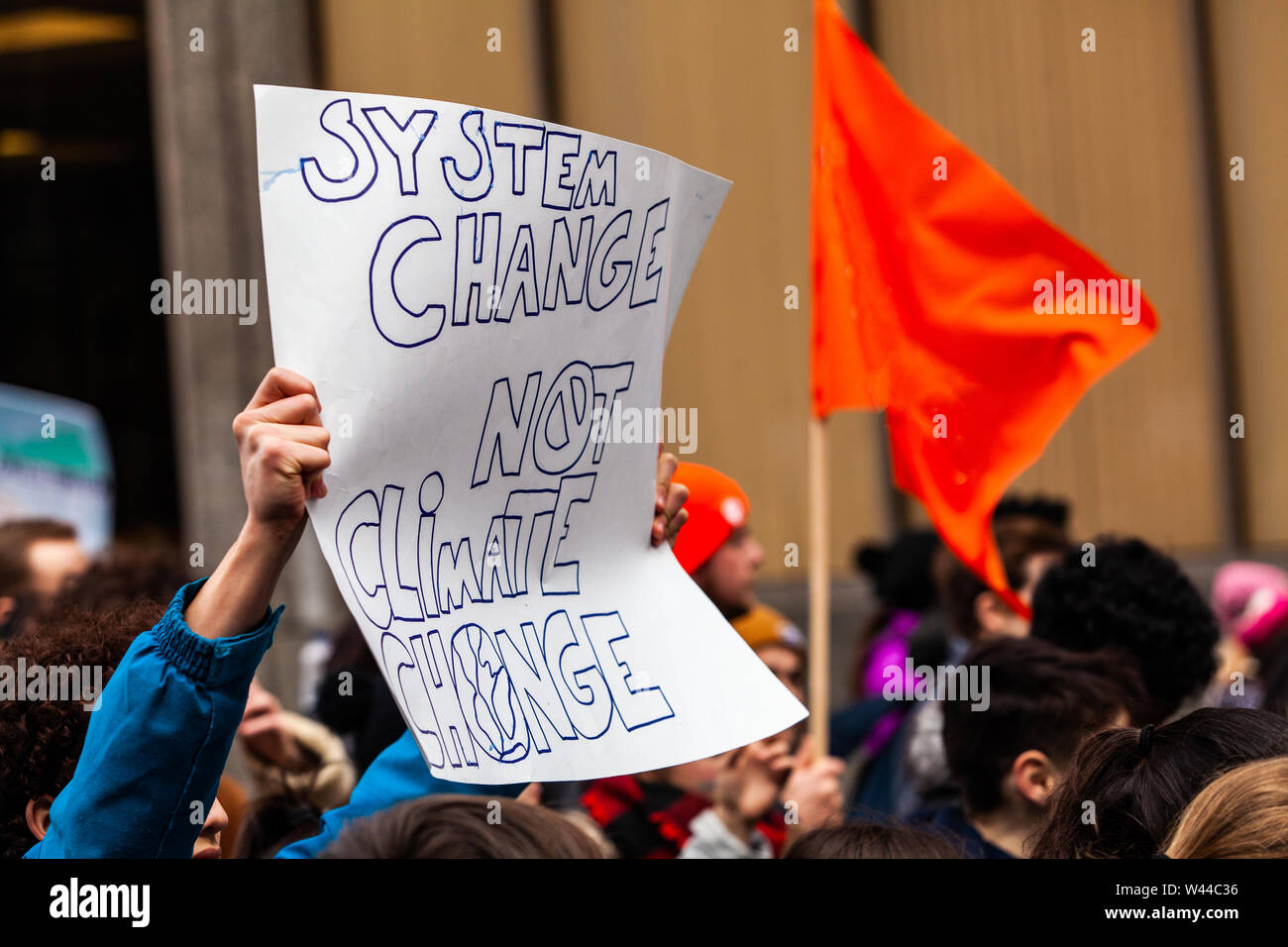 A poster is viewed close-up, saying system change not climate change ...
