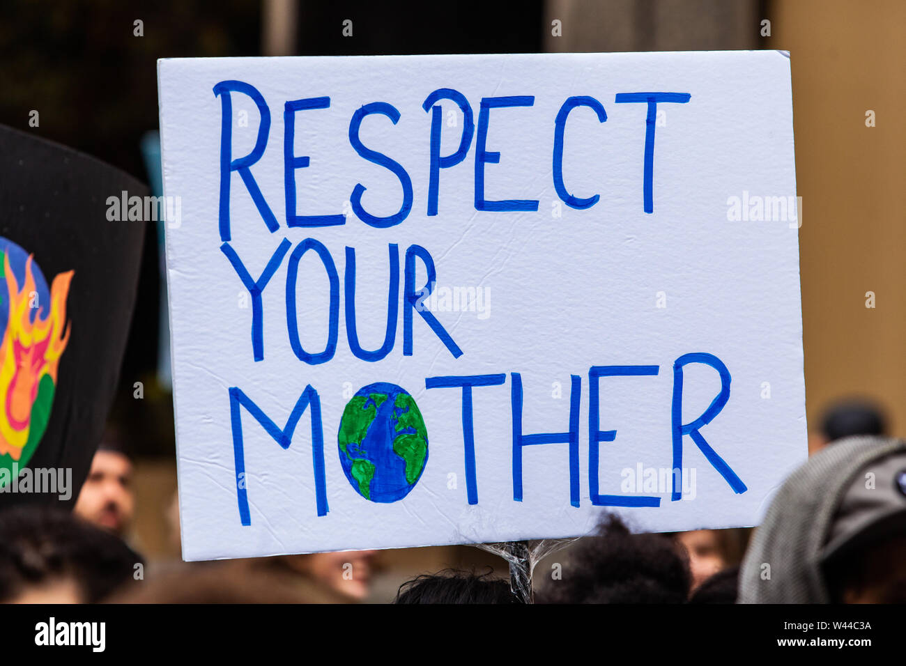 Protestors are viewed close-up, holding a poster saying respect your ...