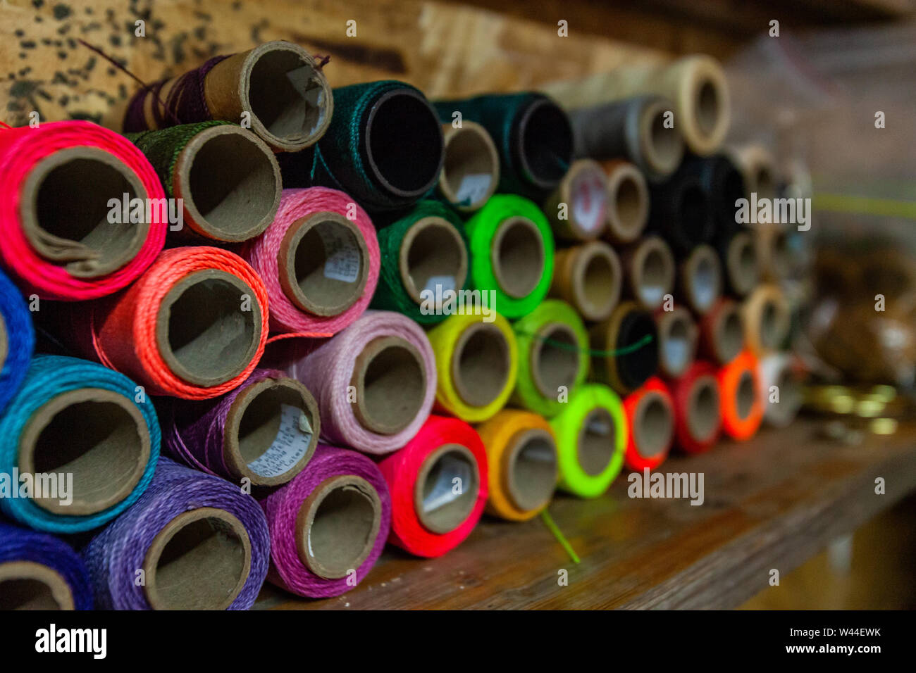 A close-up view of many colored thread spools stored on shelving inside ...