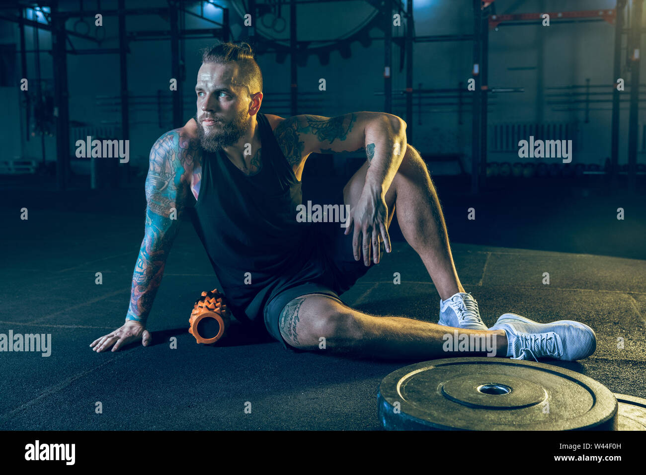 Young healthy man athlete doing exercise with the roller in the gym ...