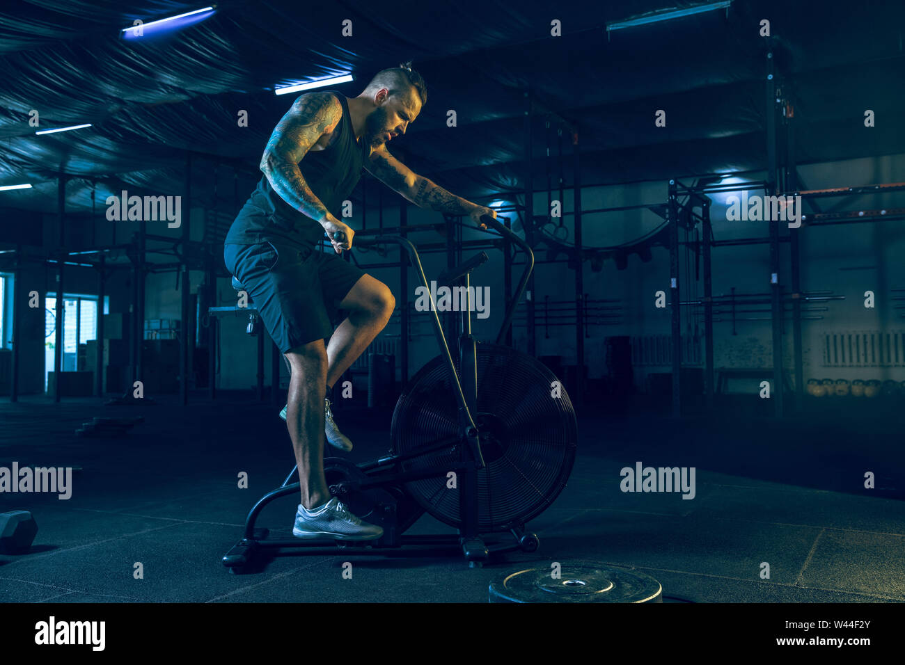 Young healthy man athlete doing exercise with the exercycles in gym ...