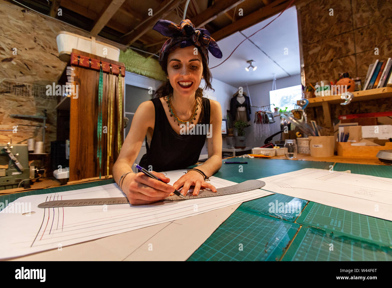 A trendy clothes maker looks happy as she illustrates new garment on a ...