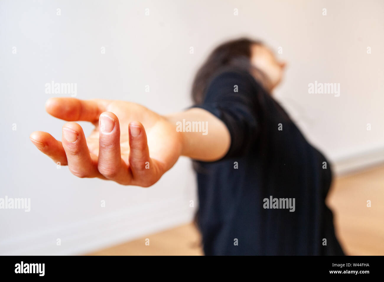 A lady's hand is viewed close up, as she stretches her blurry body away ...