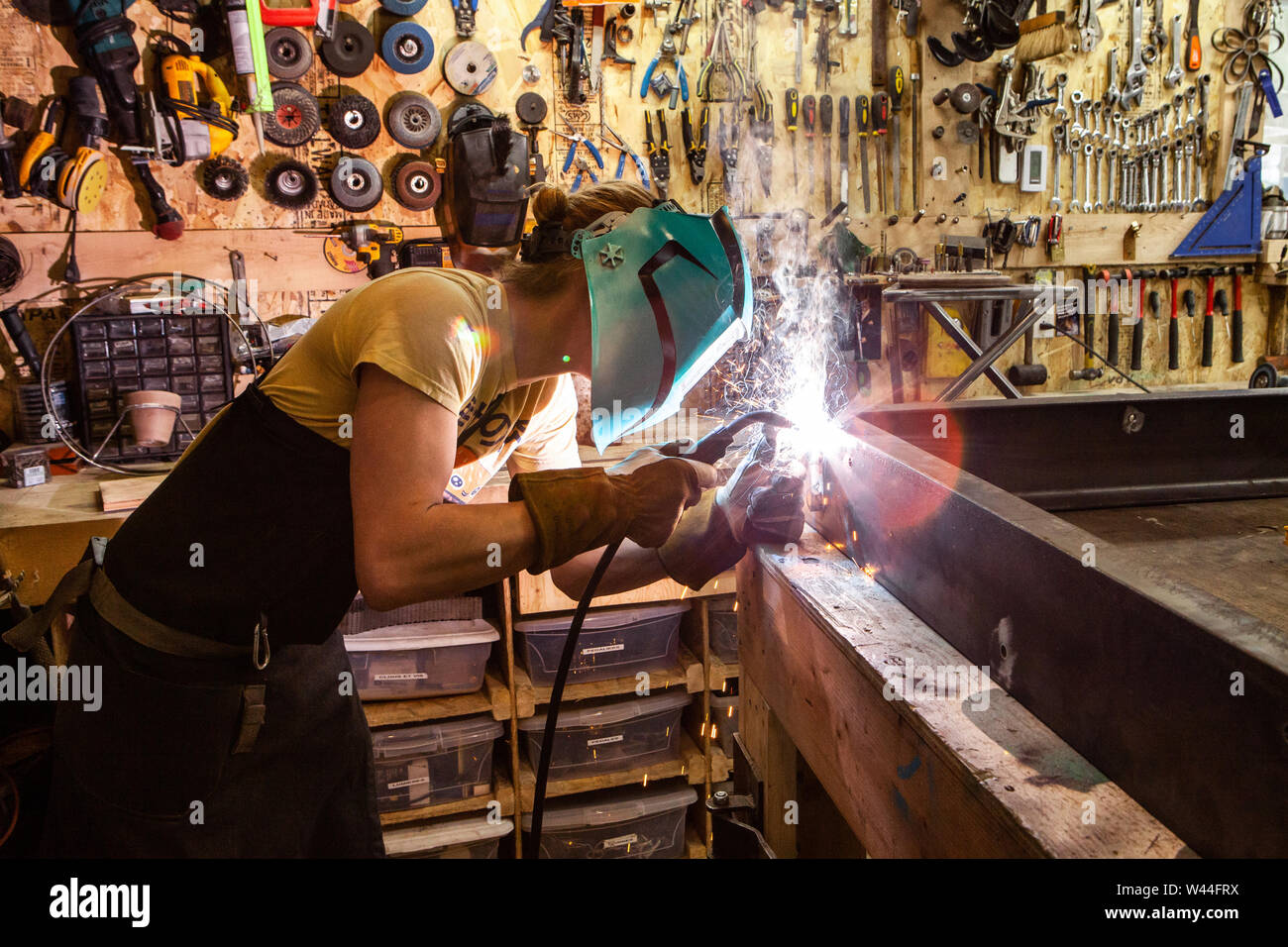 A side profile view of a blacksmith concentrating on welding two steel ...