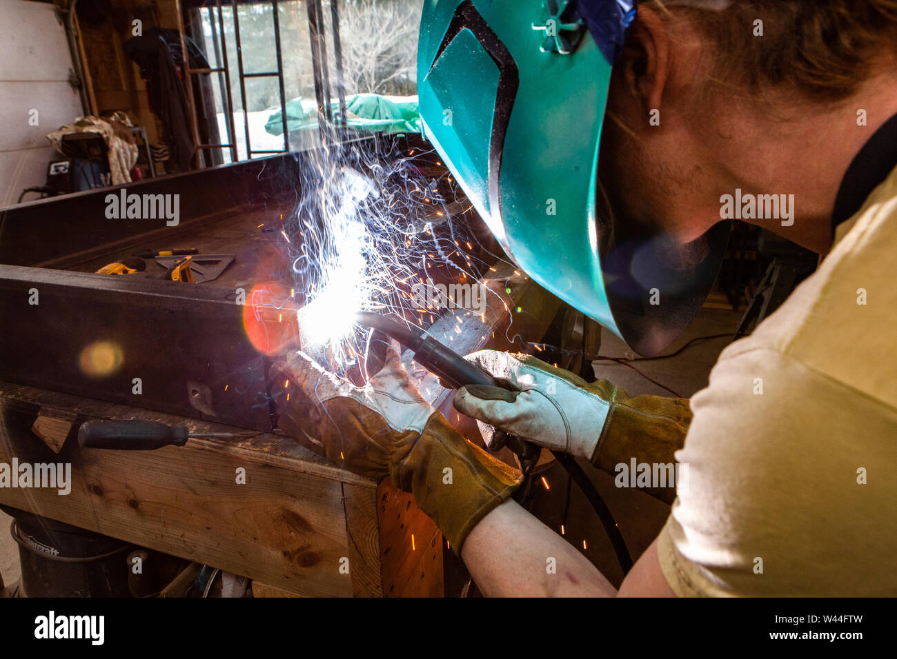 View over the shoulder of a blacksmith operating a metal inert gas ...