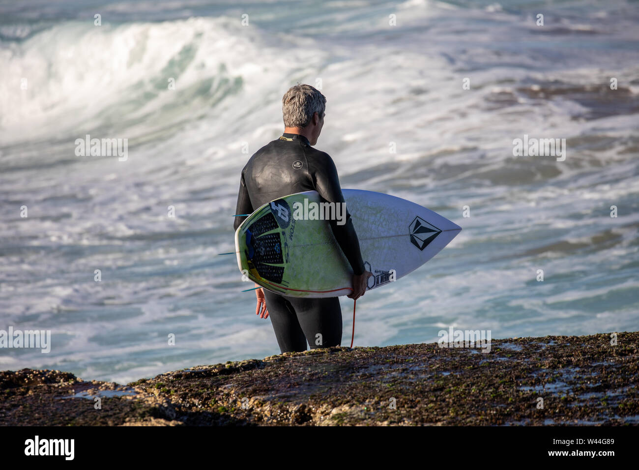 Middle aged australian make in wetsuit heads to the ocean for a surf ...