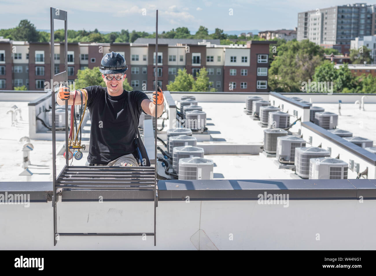 Hvac technician holding on to a roof ladder with central air ...