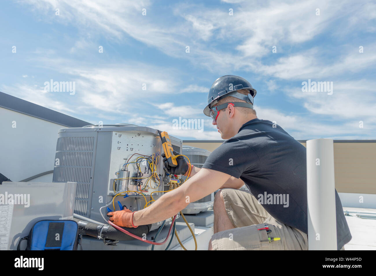 Hvac tech working on a condensing unit rooftop Stock Photo - Alamy