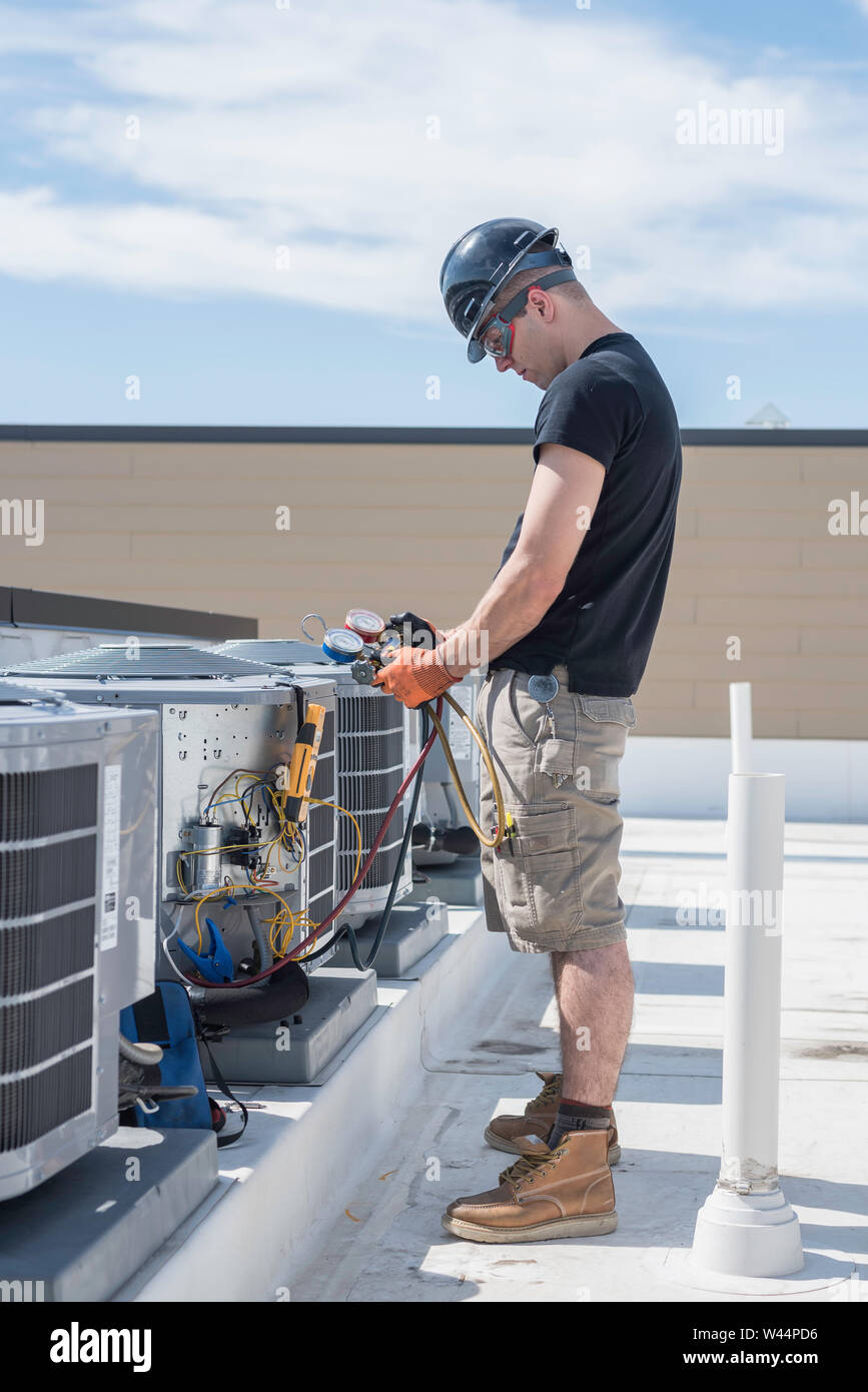 Hvac tech looking at his gauges that are hooked up to a condensing unit ...