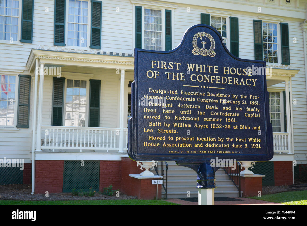 An historical blue metal sign with gold text in front of the First ...