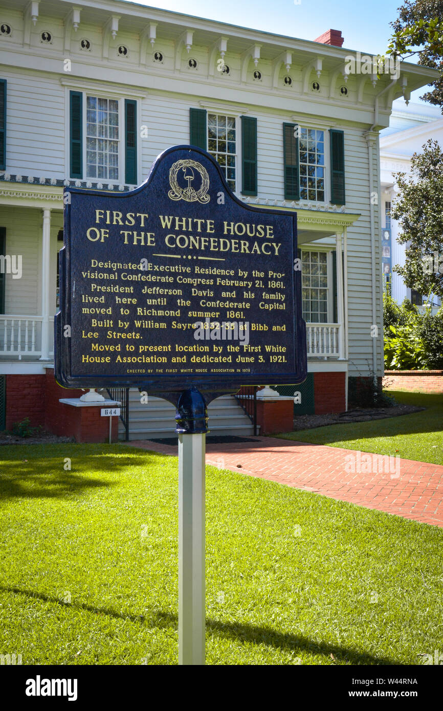 An histoical blue metal sign with gold text in front of the First White ...