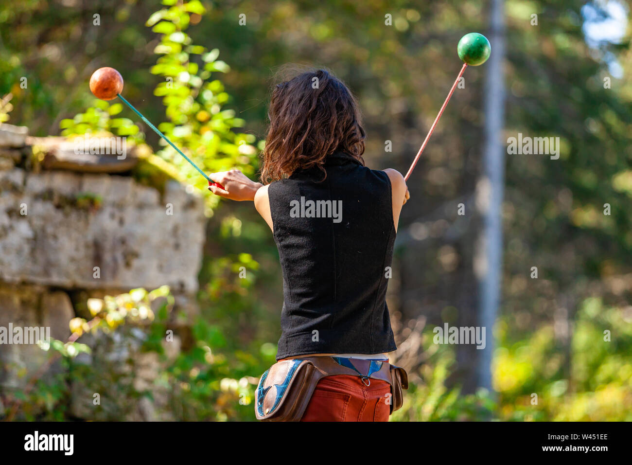 An entertainer is viewed from behind, swinging balls against a blurred ...