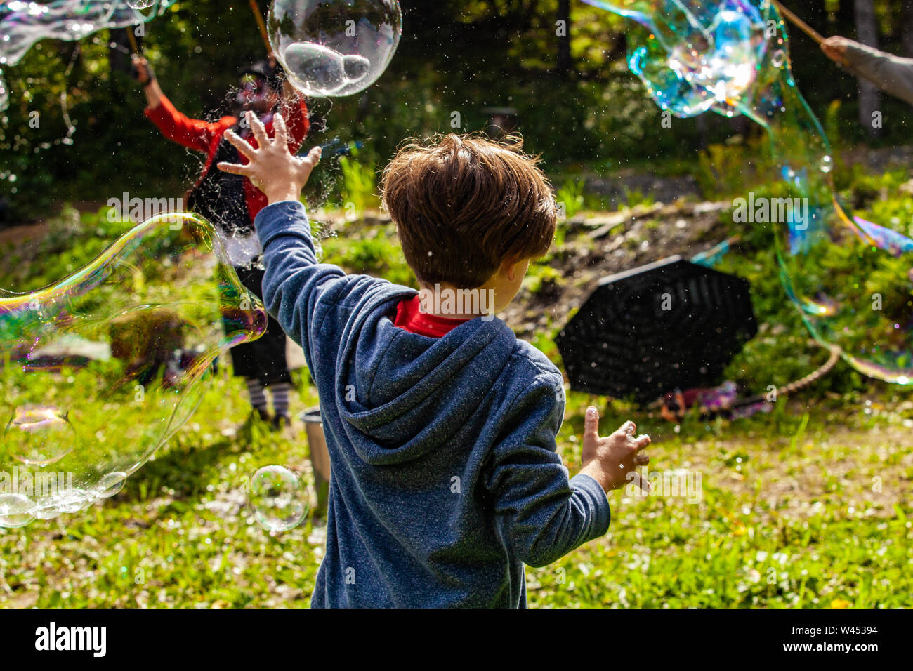 A young boy is viewed from behind trying to catch bubbles at a native ...