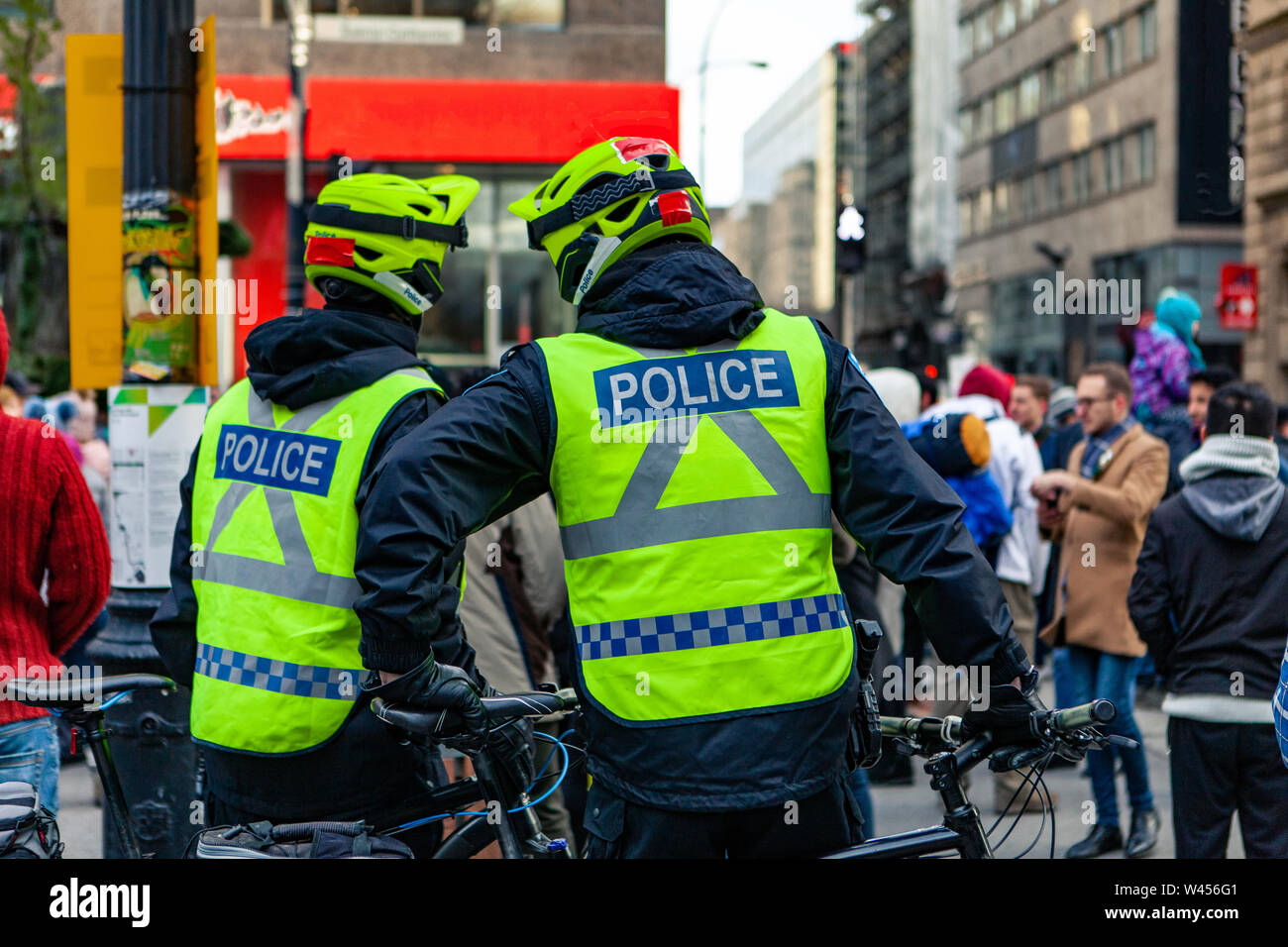 A rear view of two police cyclists standing by their patrol bikes and ...