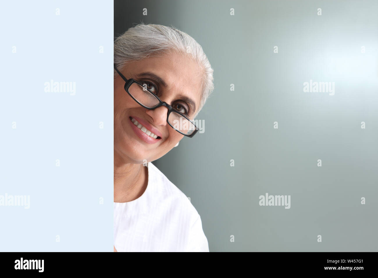 Woman hiding behind wall a watching High Resolution Stock Photography ...