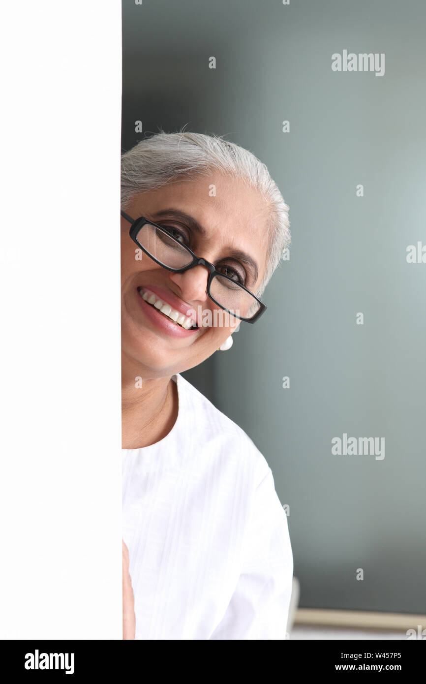Portrait of a woman hiding behind a placard and smiling Stock Photo - Alamy