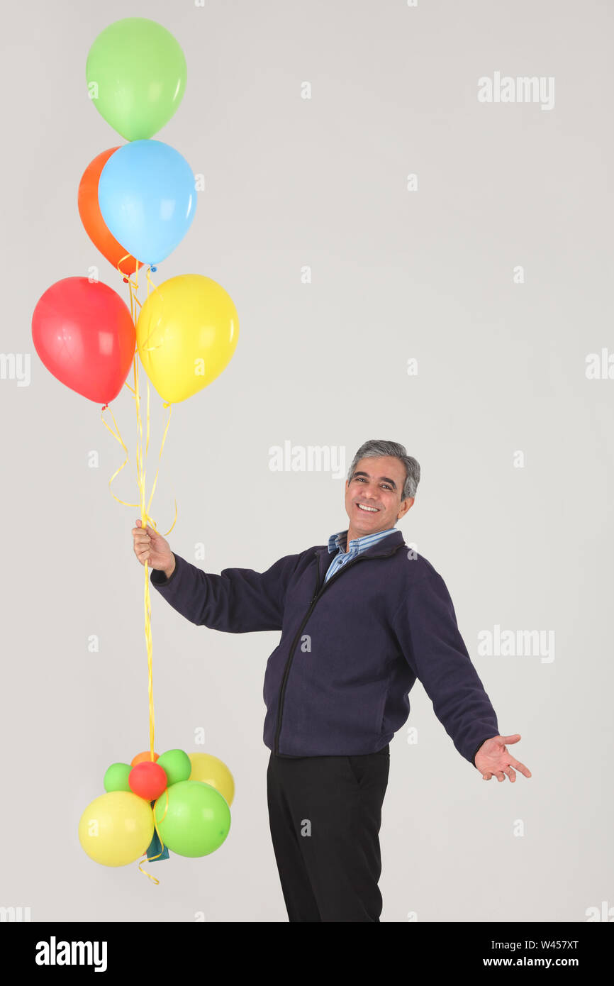 Portrait of a man holding balloons and smiling Stock Photo - Alamy