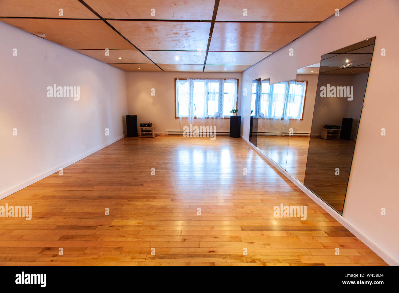 A wide angled view of a large room with parquet flooring and mirrors ...