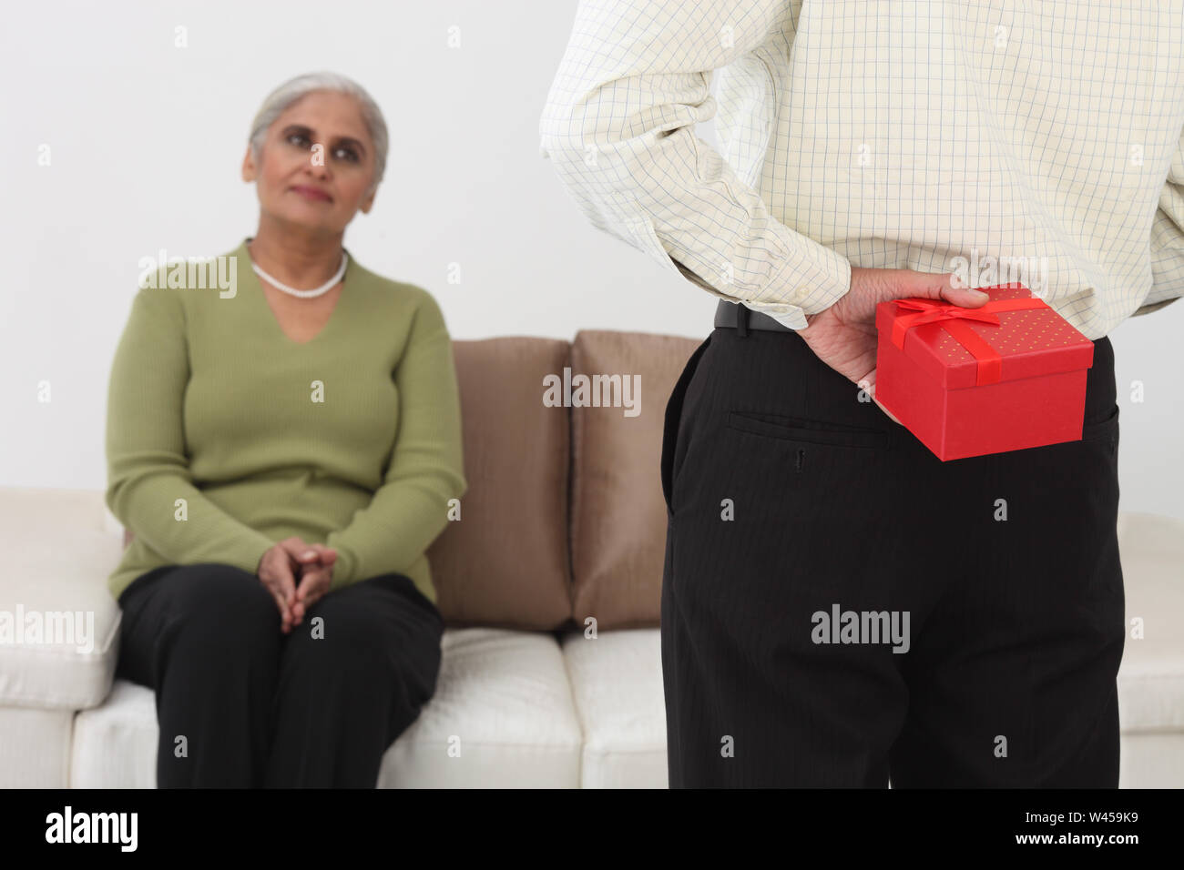Man hiding gift behind back from his wife Stock Photo - Alamy
