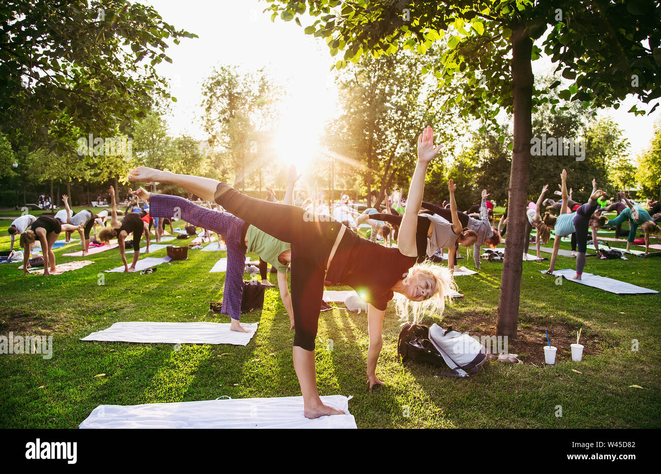 big group of adults attending a yoga class outside in park Stock Photo ...