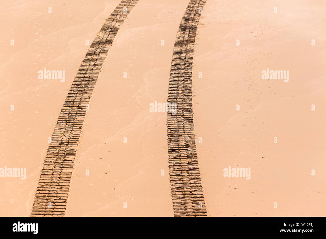 Vehicle machine tracks imprints on beach sand though the frame overhead ...