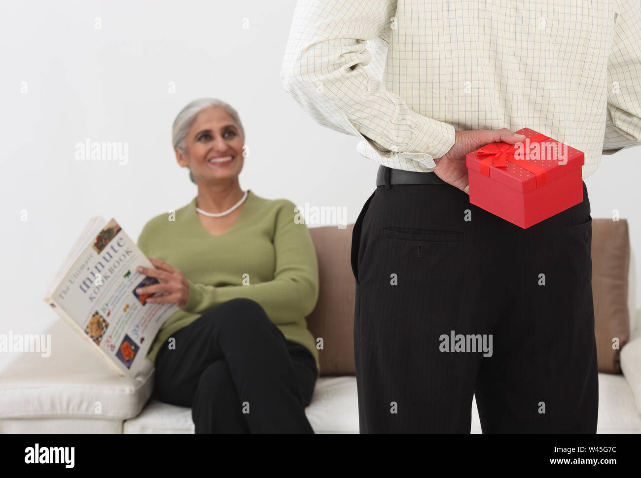 Man hiding gift behind back from his wife Stock Photo - Alamy